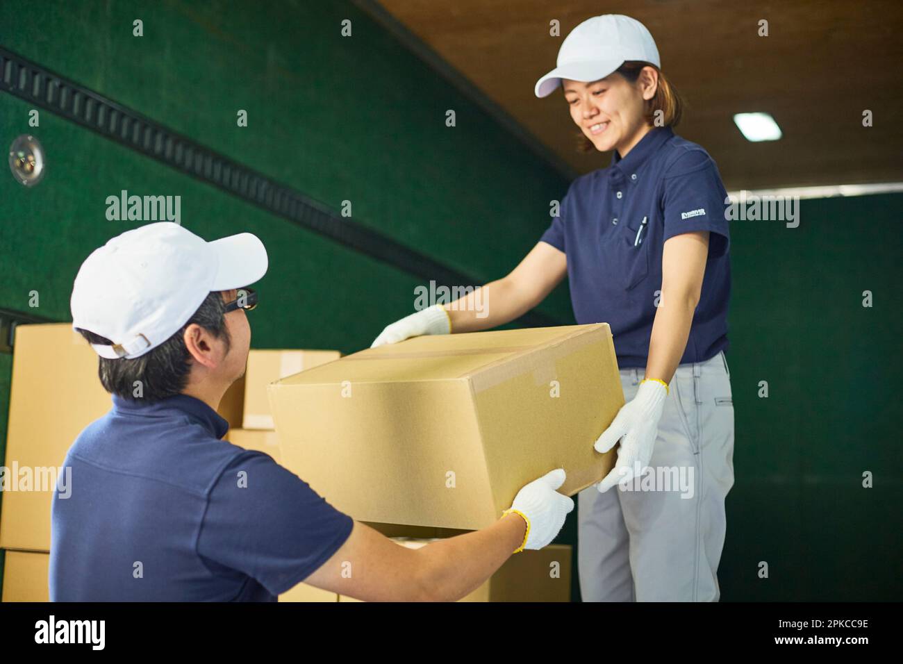 Men and women in work clothes loading cardboard boxes onto a truck Stock Photo - Alamy