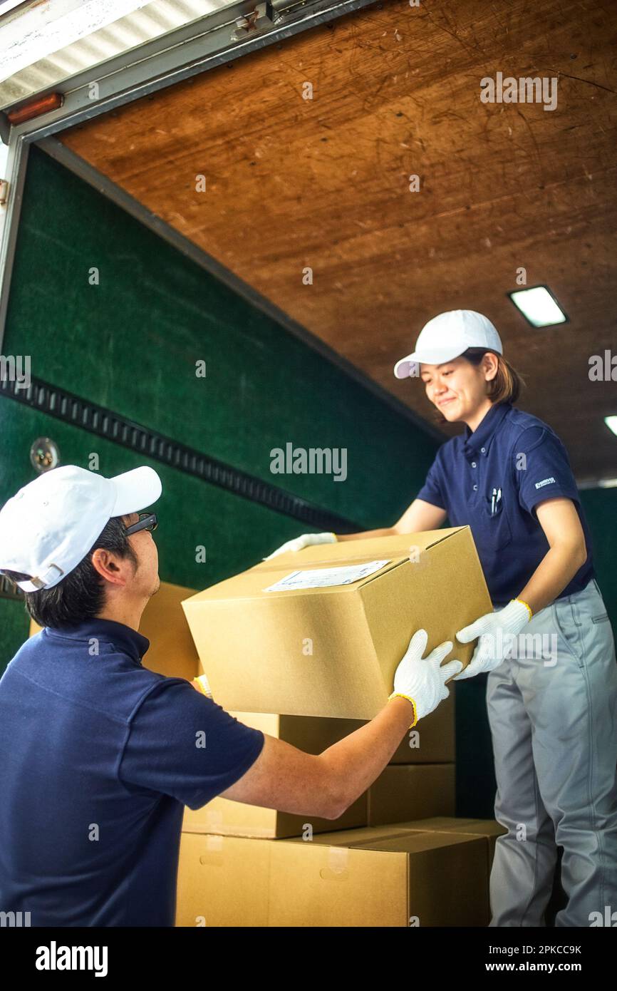 Men and women in work clothes loading cardboard boxes onto a truck ...