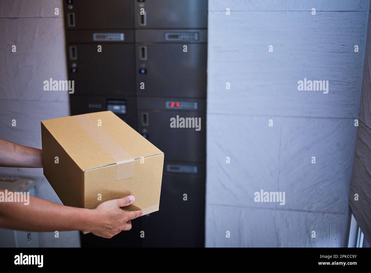 Man with a cardboard box standing in front of a delivery box Stock ...
