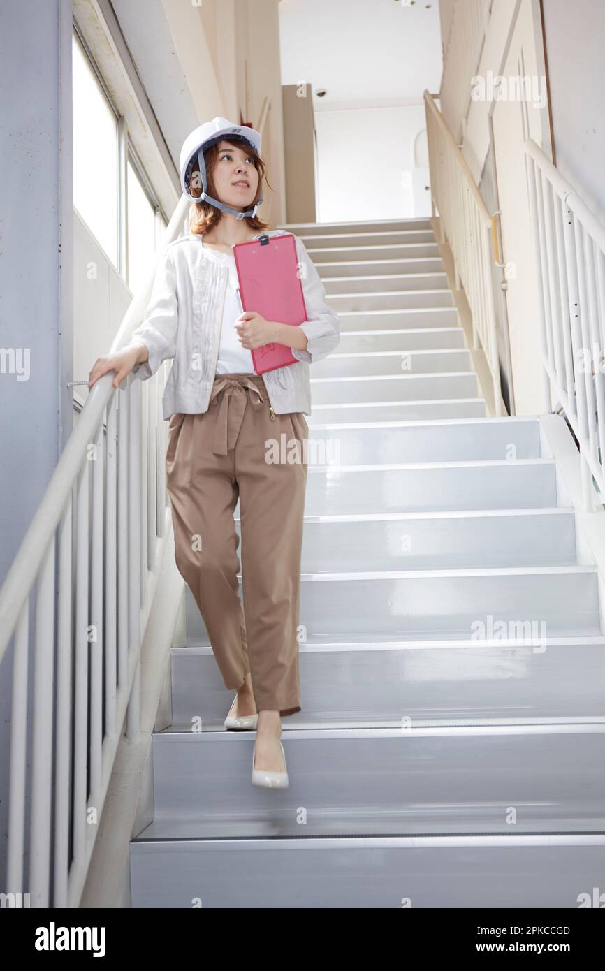 Woman wearing a helmet and carrying papers while descending stairs Stock Photo - Alamy
