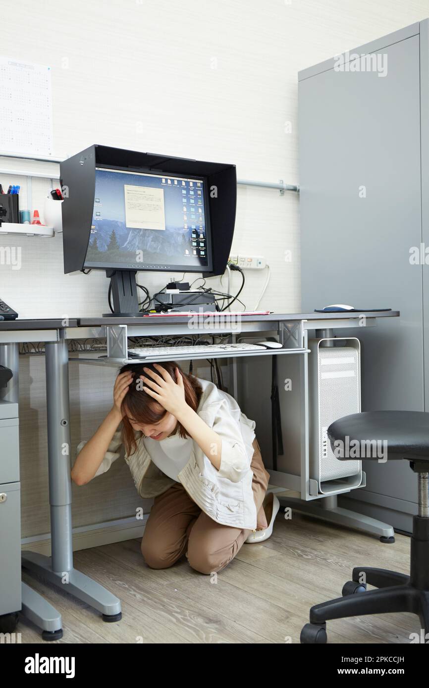 Woman hiding under a desk in office Stock Photo - Alamy