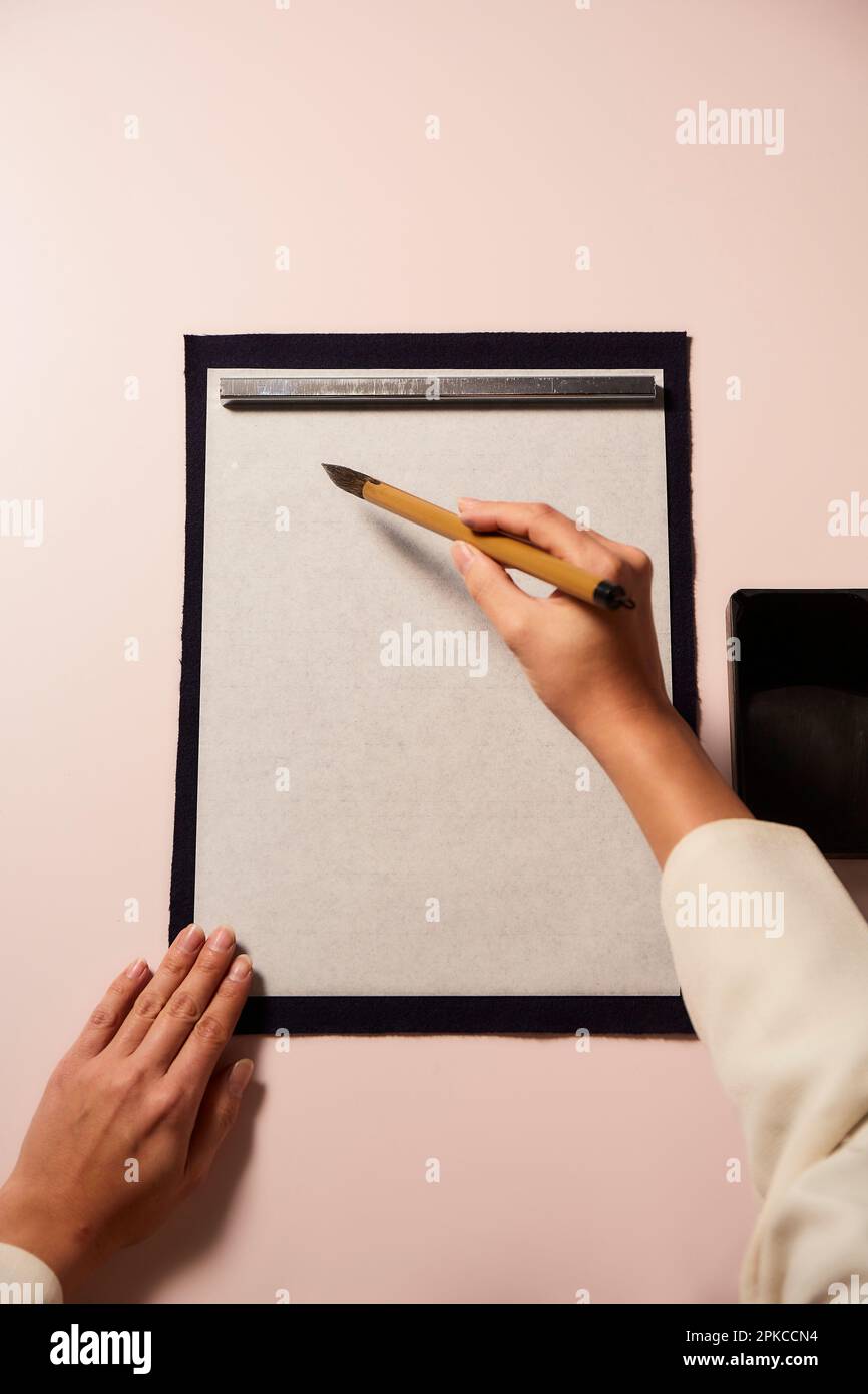 Woman's hand doing calligraphy on light pink background Stock Photo - Alamy