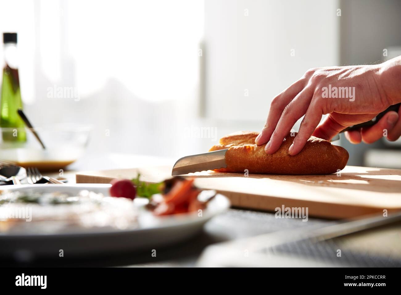 Man cutting baguette Stock Photo - Alamy