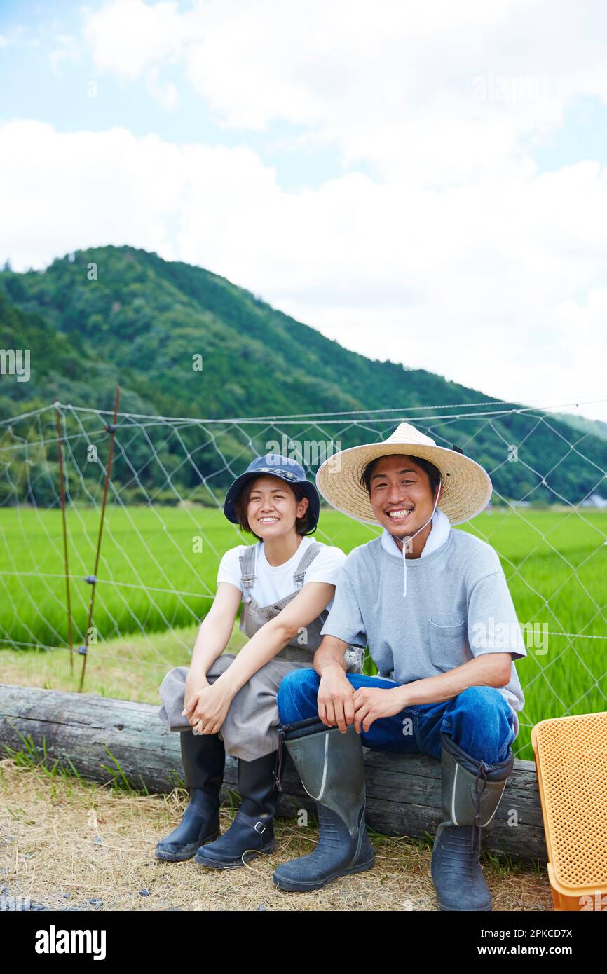 Smiling men and women sitting on a log in front of a paddy field Stock ...