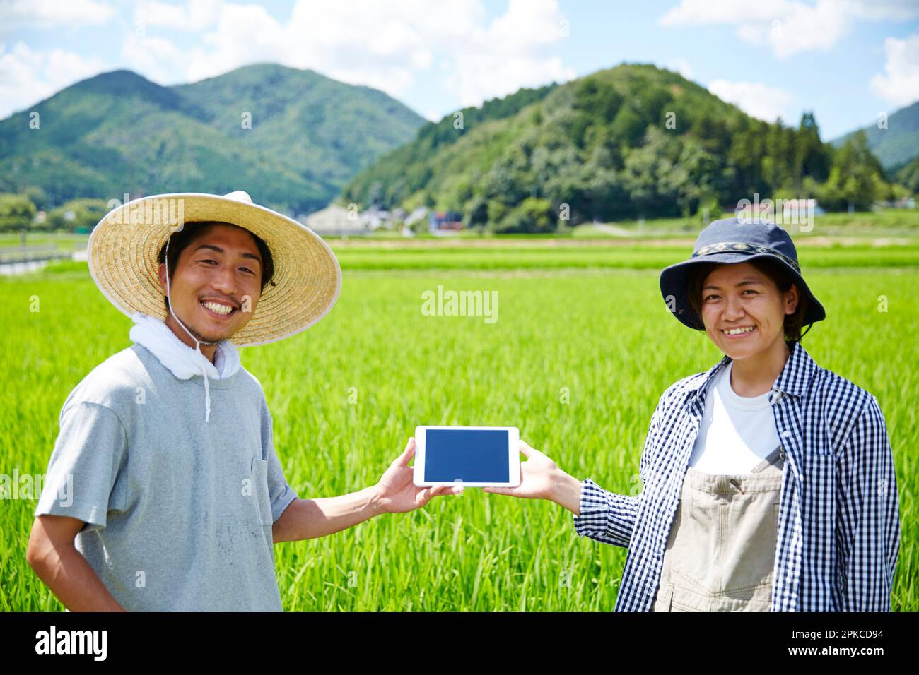 Man and woman holding tablets in front of paddy field Stock Photo - Alamy
