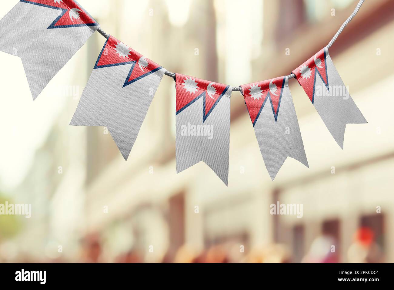 A garland of Nepal national flags on an abstract blurred background ...