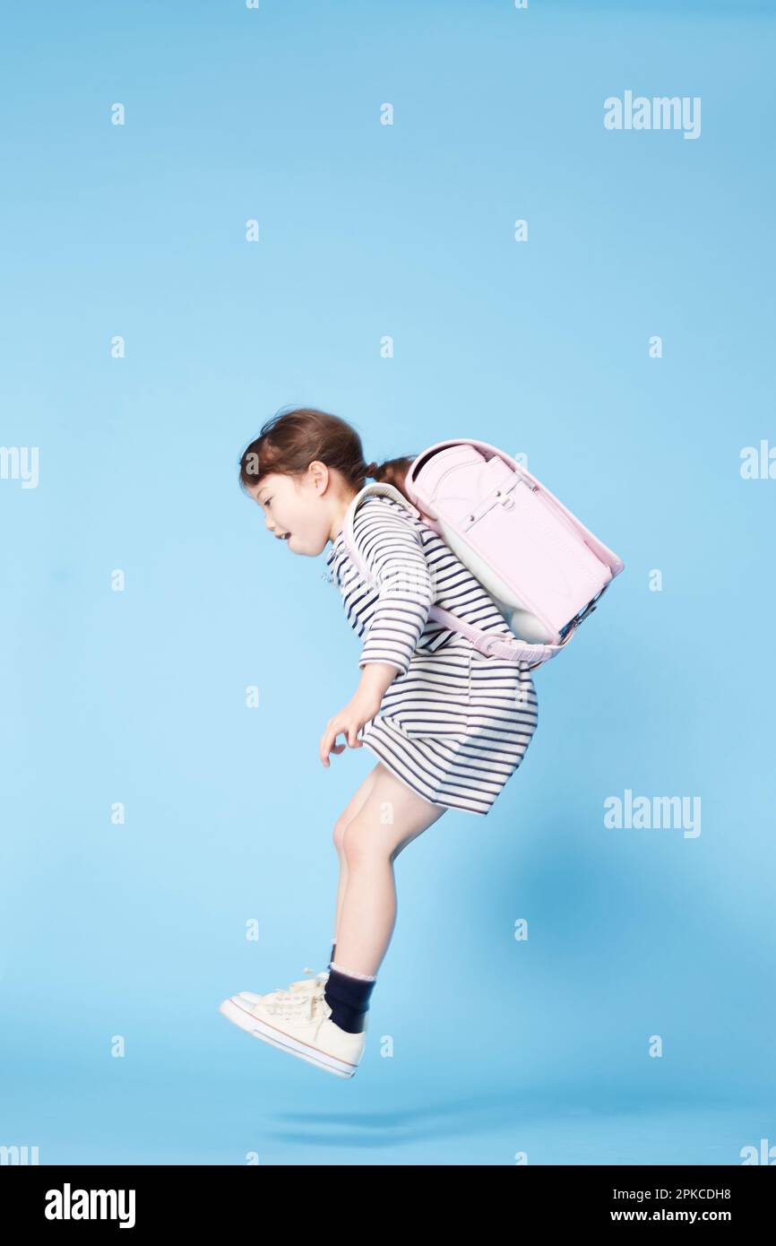 Girl with school backpack jumping Stock Photo - Alamy