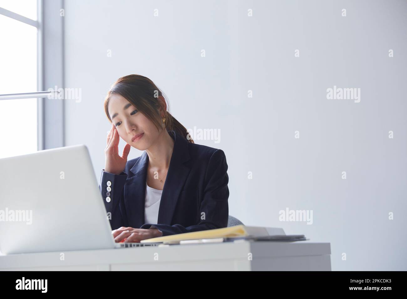 A woman at her desk at work looking gloomily at her computer Stock ...