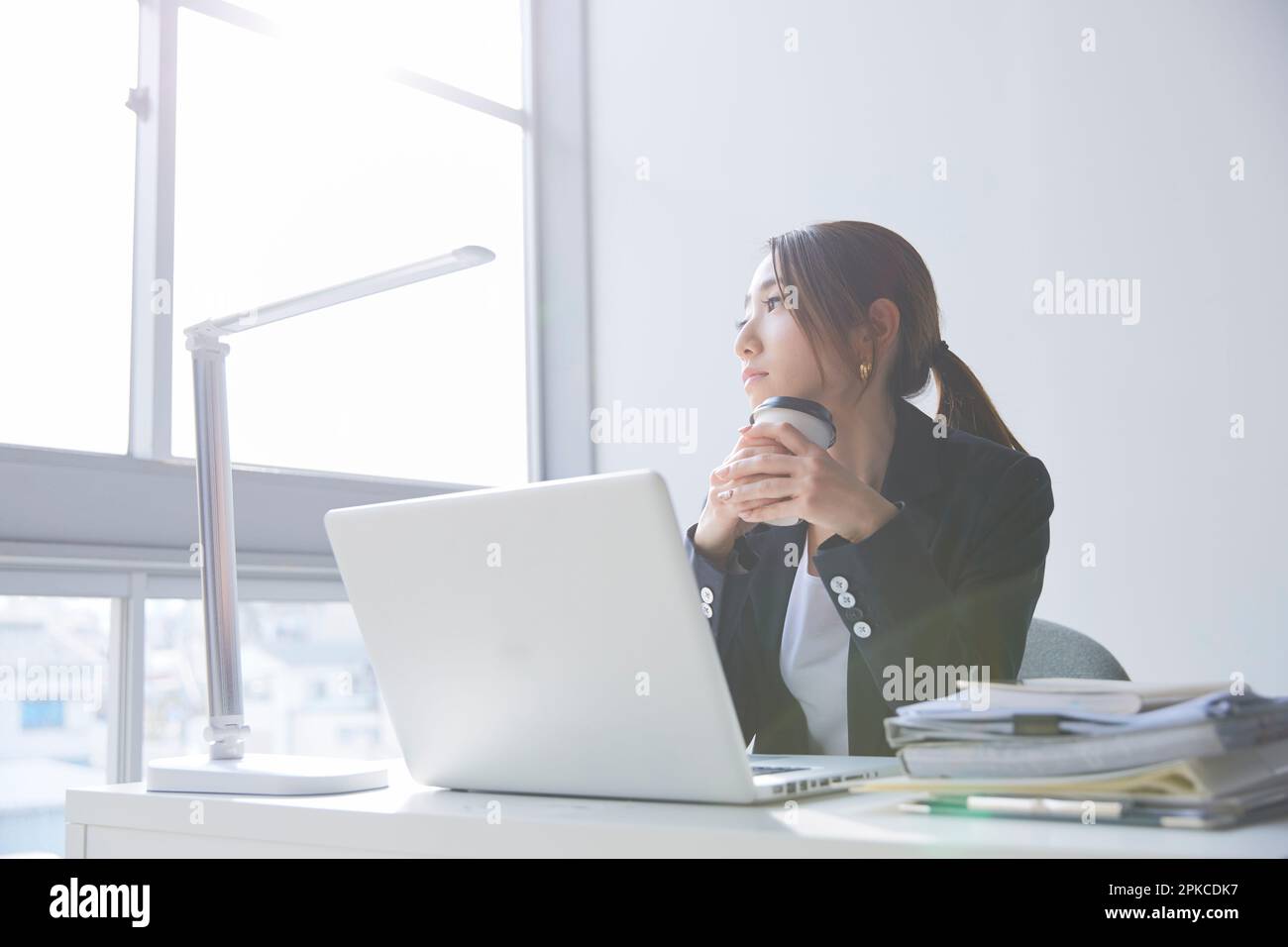 A woman at her desk at work looking out the window with a gloomy ...