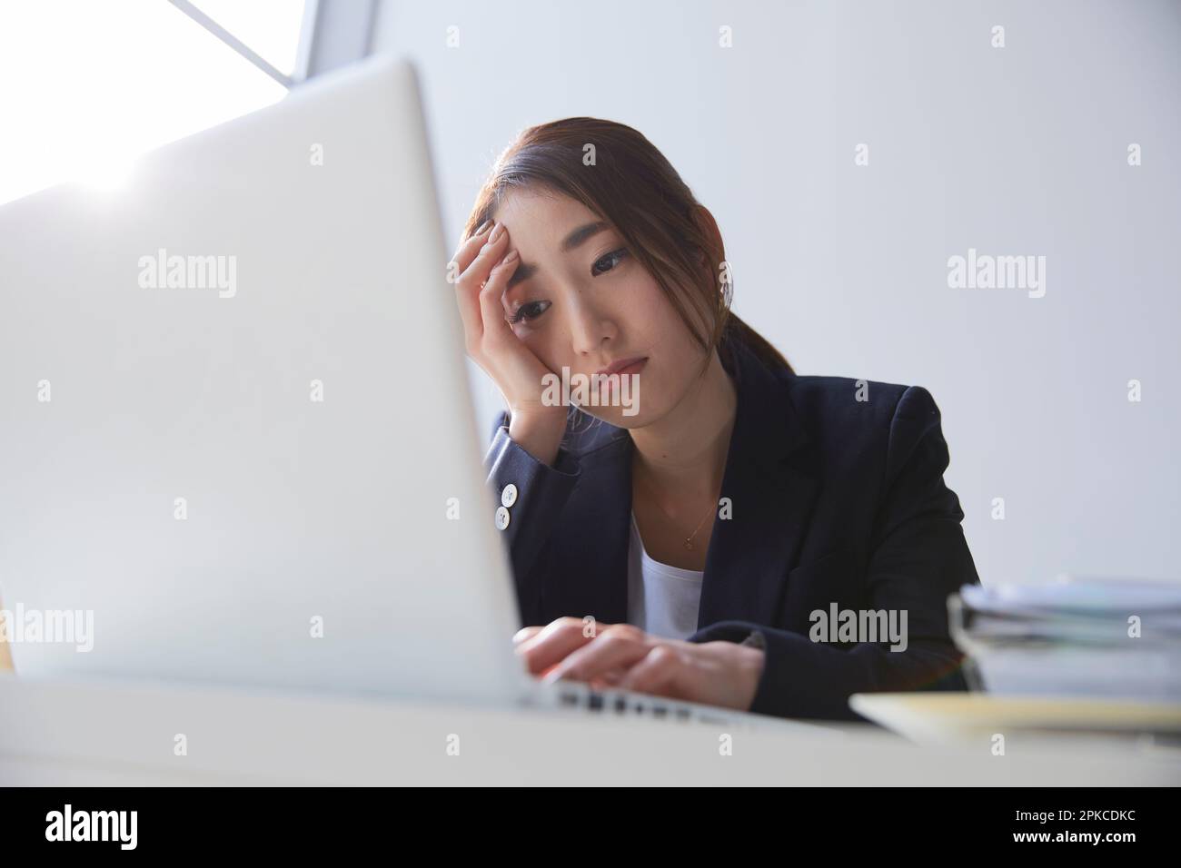 Woman with a dark expression on her face looking at her computer at her ...