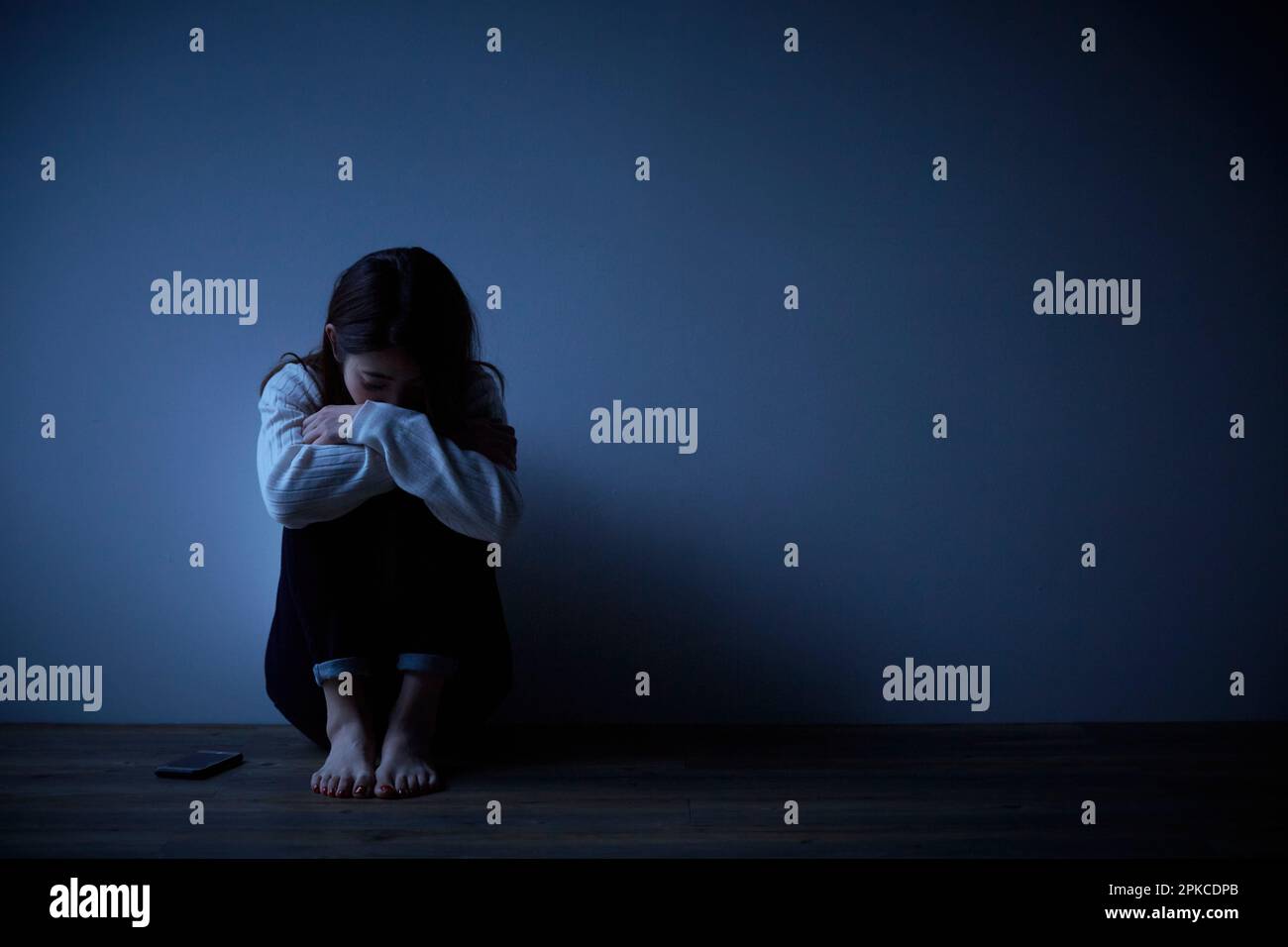 Woman getting smaller in a dark room Stock Photo - Alamy