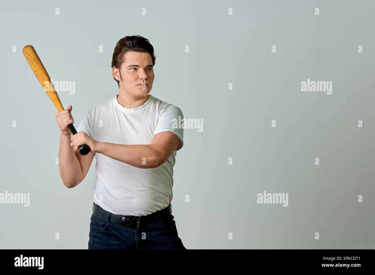 A man with a bat in his hands swings on a gray background Stock Photo ...