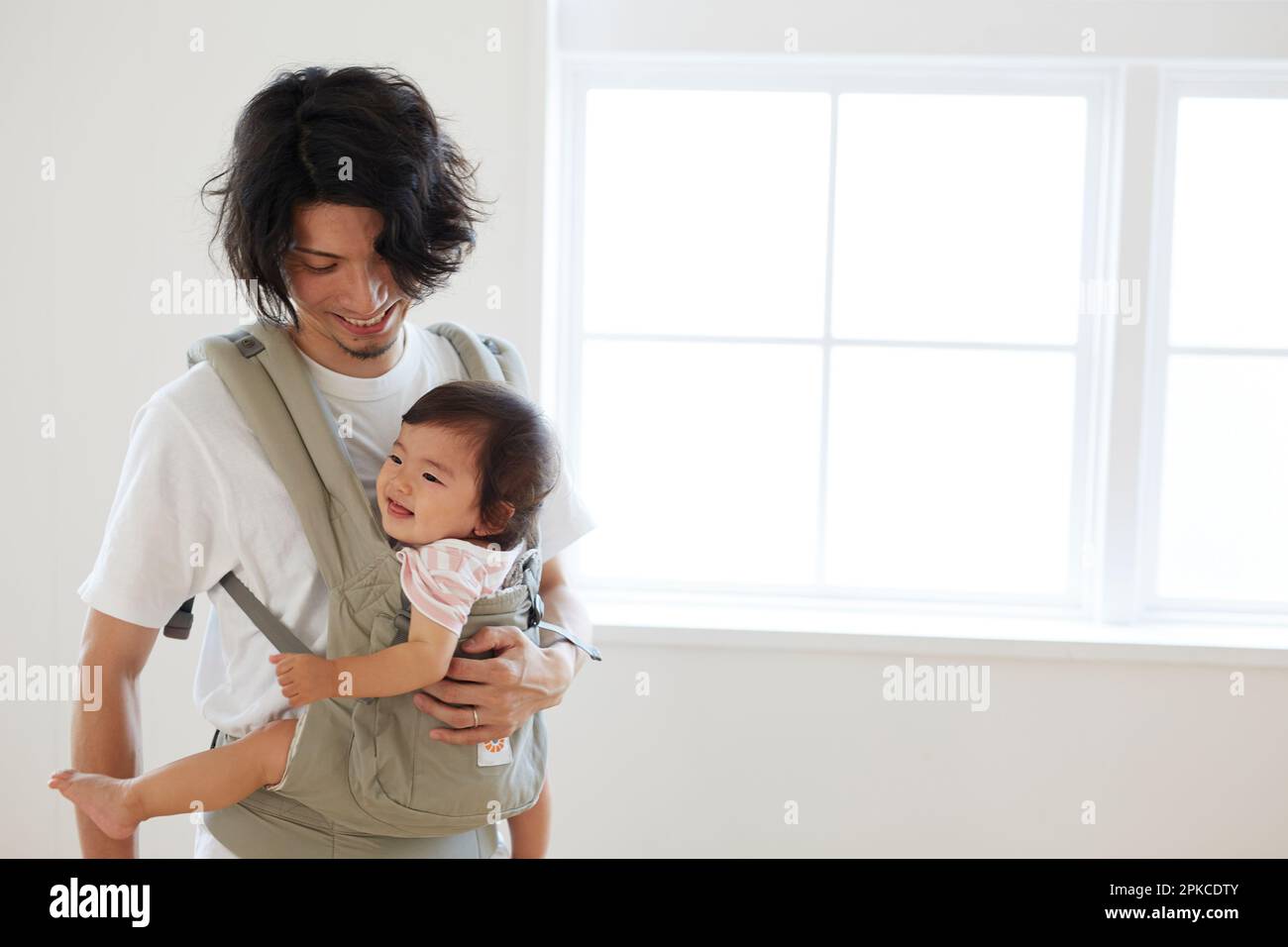 Baby being carried by father in front of window Stock Photo - Alamy