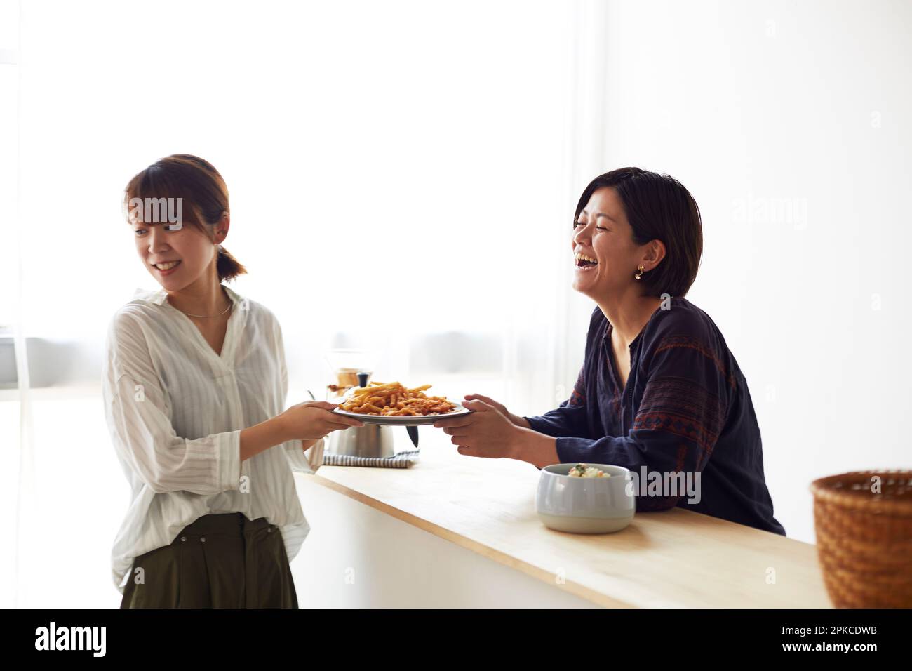Two women handing over plates of food Stock Photo - Alamy