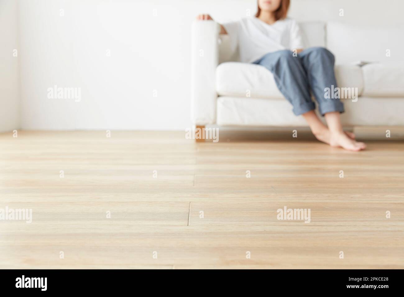 Woman sitting on white sofa in simple room Stock Photo - Alamy