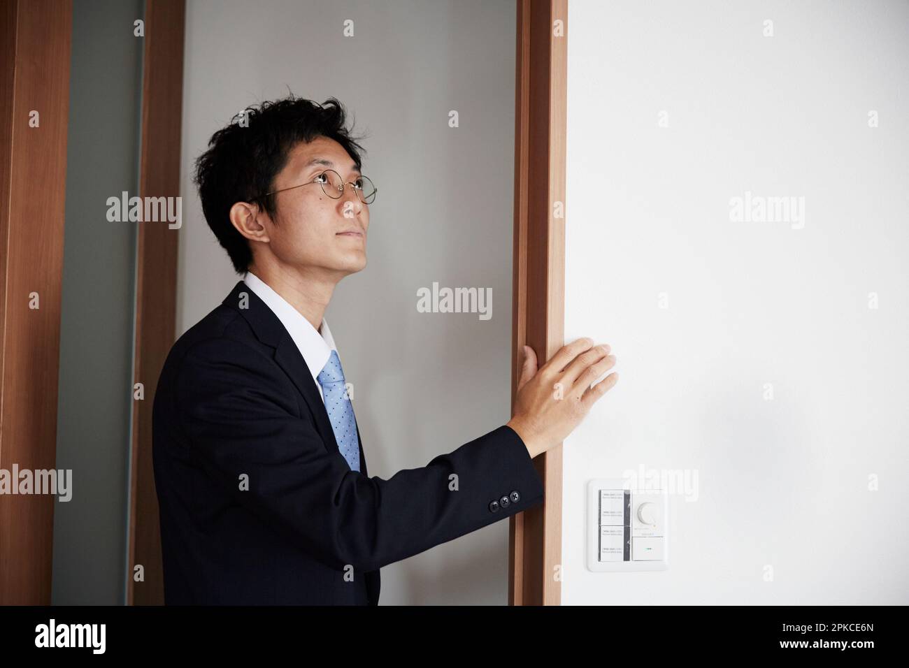 Man in suit with his hand on the wall Stock Photo - Alamy
