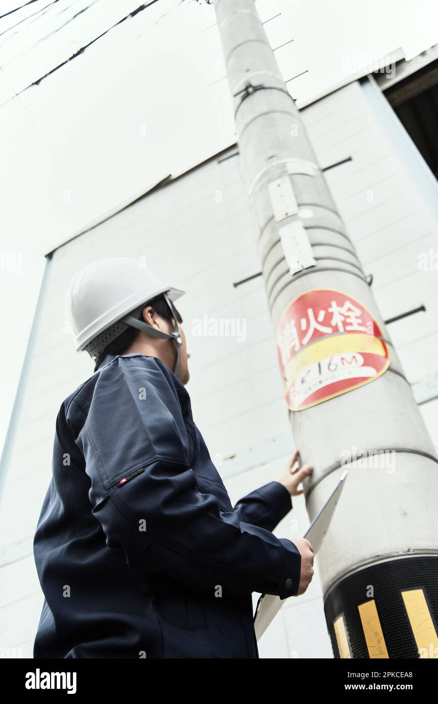 A man in work clothes facing a utility pole Stock Photo - Alamy