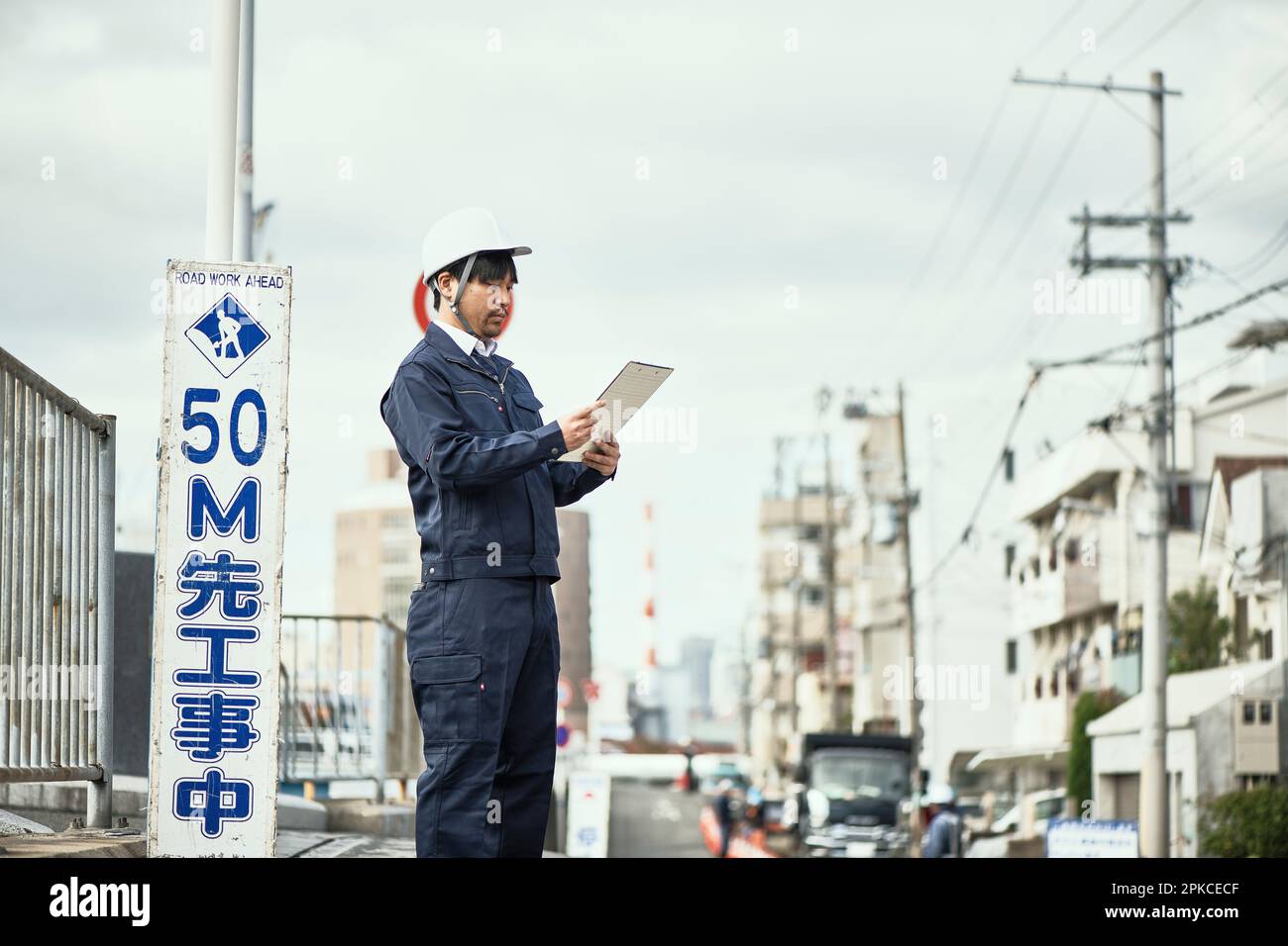 Man in work clothes and helmet looking at hand Stock Photo - Alamy