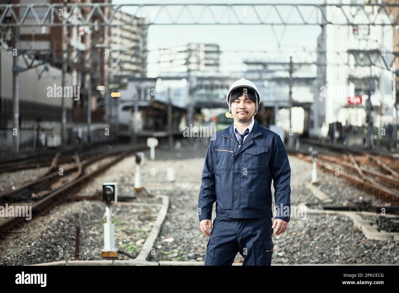 Man in work clothes and helmet standing on railroad tracks Stock Photo ...
