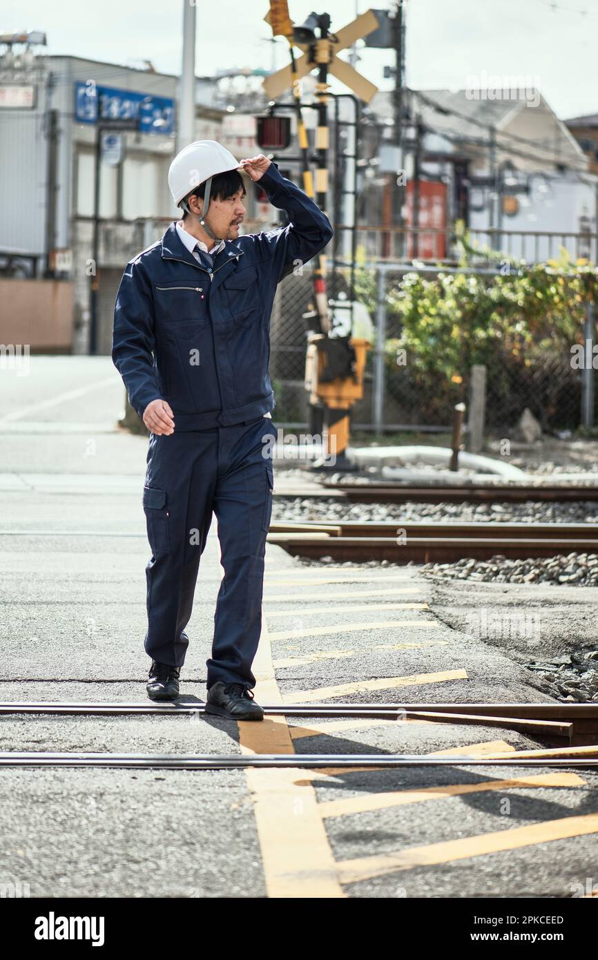 Man in work clothes and helmet crossing railroad tracks Stock Photo - Alamy