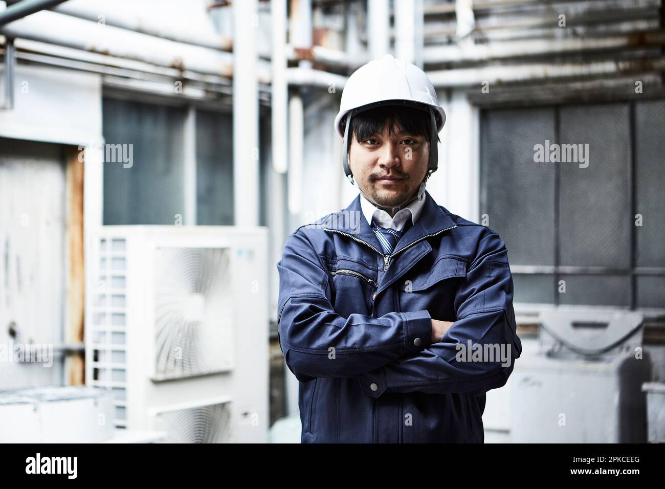 Man in work clothes and helmet facing front with arms folded Stock ...