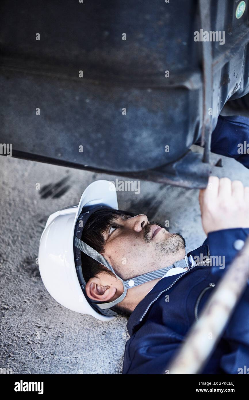 Man in work clothes and helmet working under a car Stock Photo - Alamy