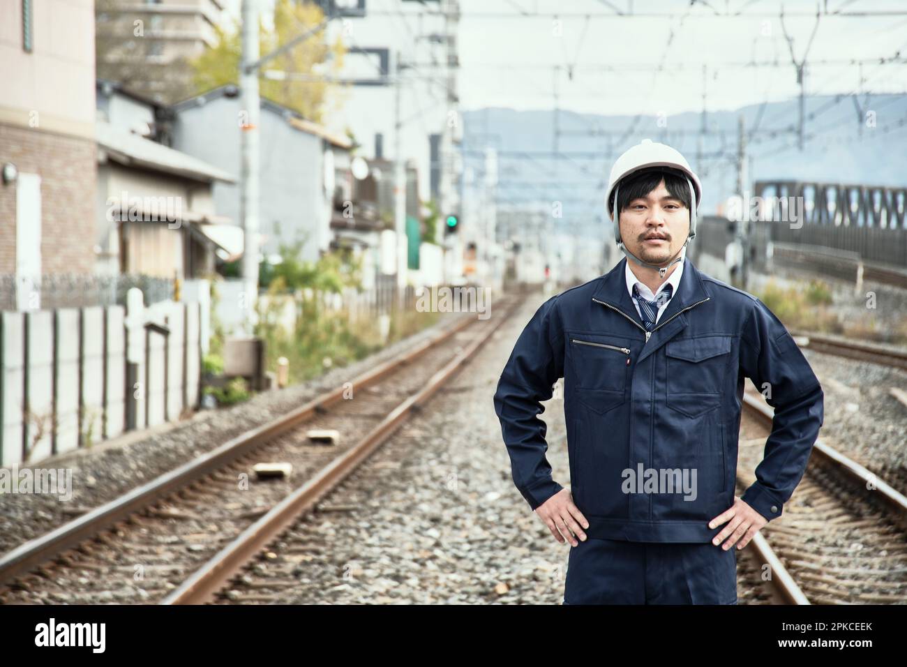 Man in work clothes and helmet standing with railroad tracks in the ...