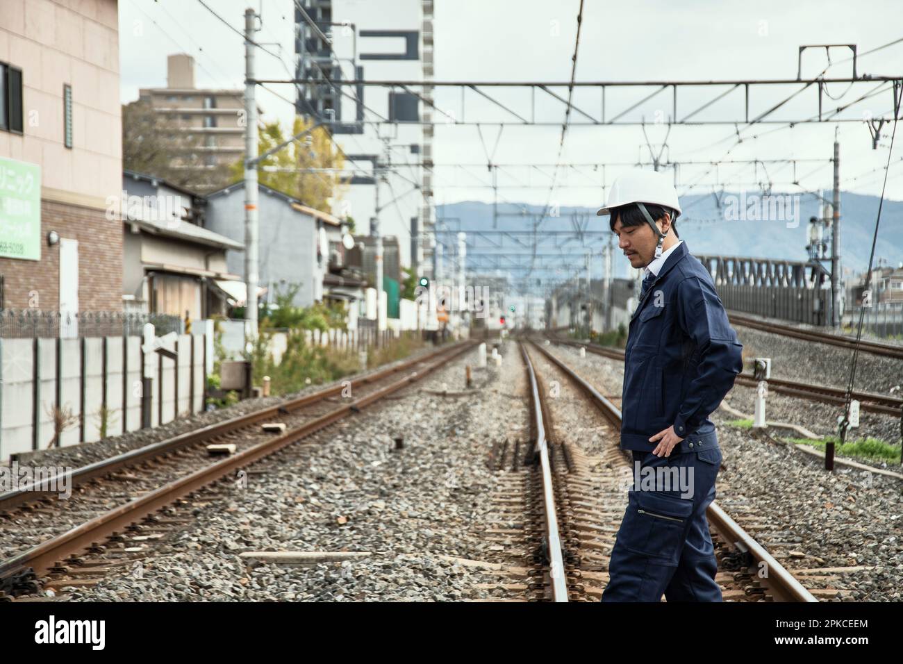 Man in work clothes and helmet crossing railroad tracks Stock Photo - Alamy