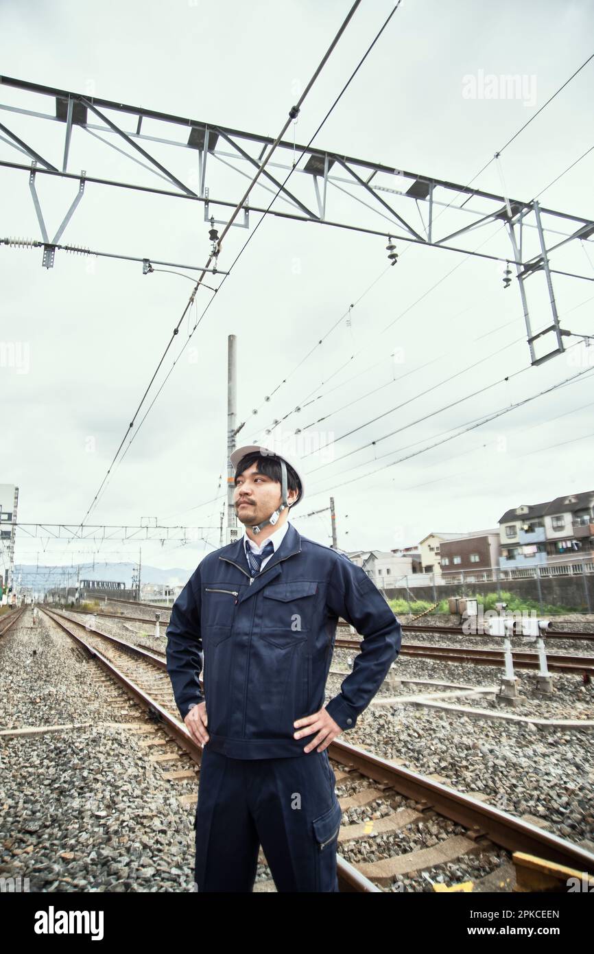 Man in work clothes and helmet standing with railroad tracks in ...