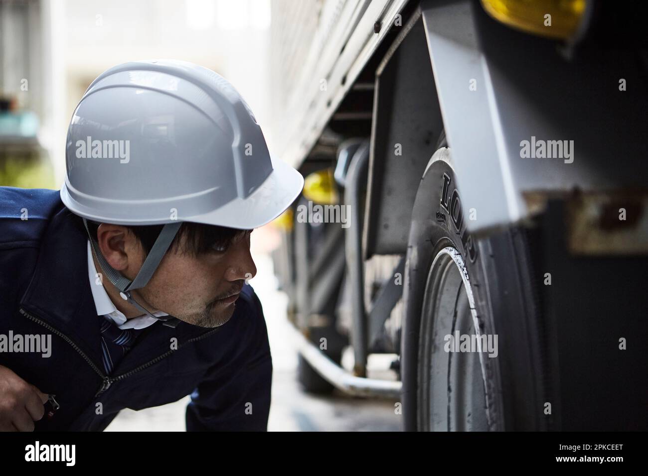 Man in work clothes and helmet looking into tire Stock Photo - Alamy