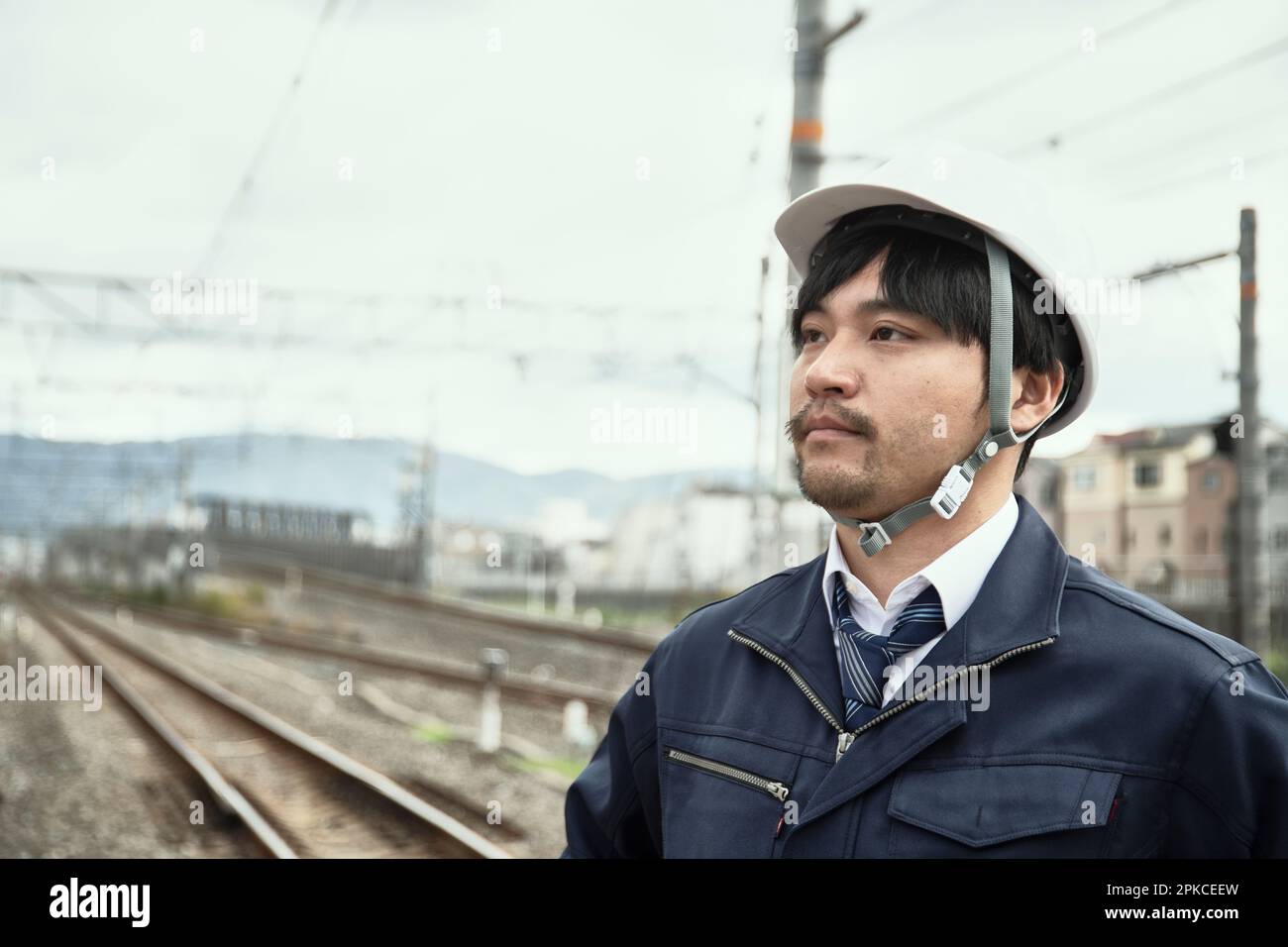 Man in work clothes and helmet standing with railroad tracks in the ...