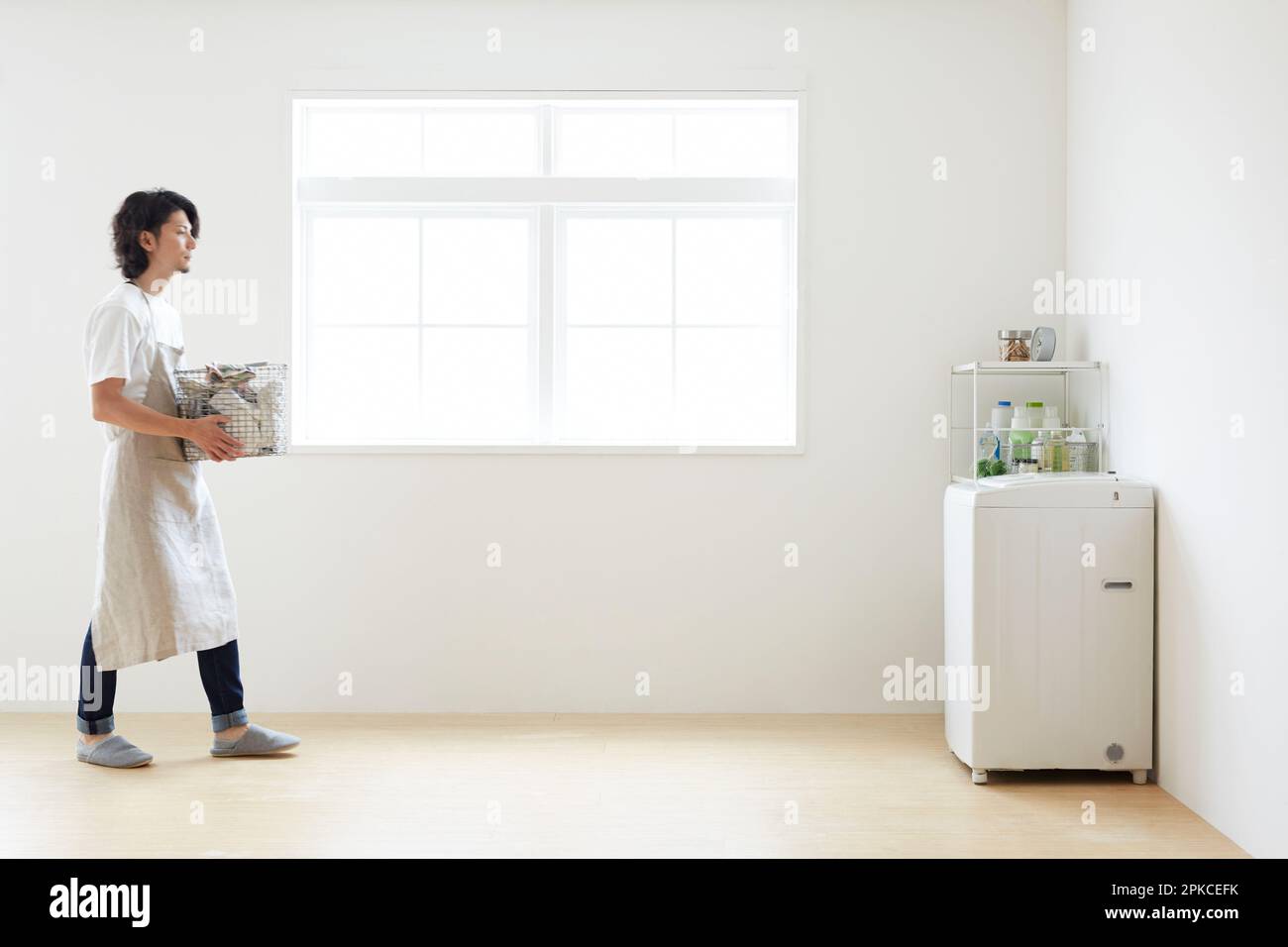 Man carrying laundry to washing machine in a simple room Stock Photo ...