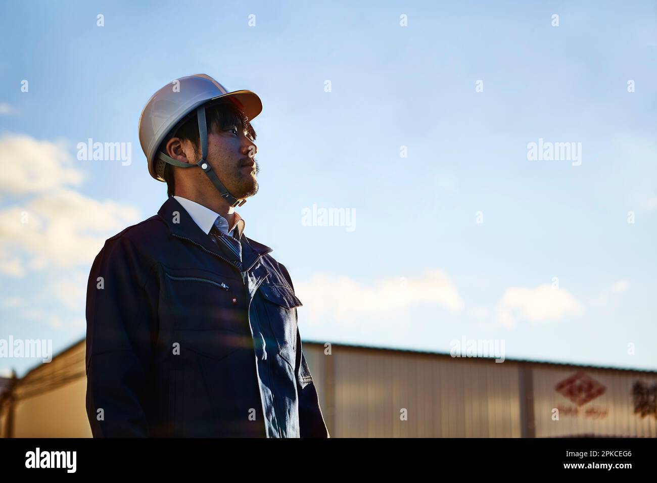 Man in work clothes and helmet looking into distance Stock Photo - Alamy
