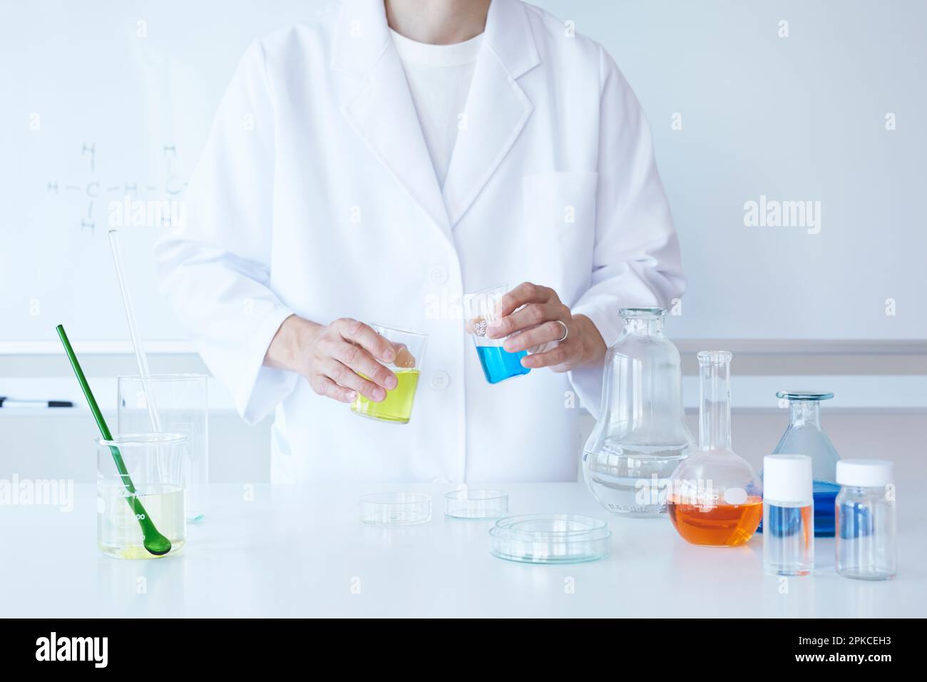 Man in lab coat experimenting with mixing colored liquid Stock Photo ...