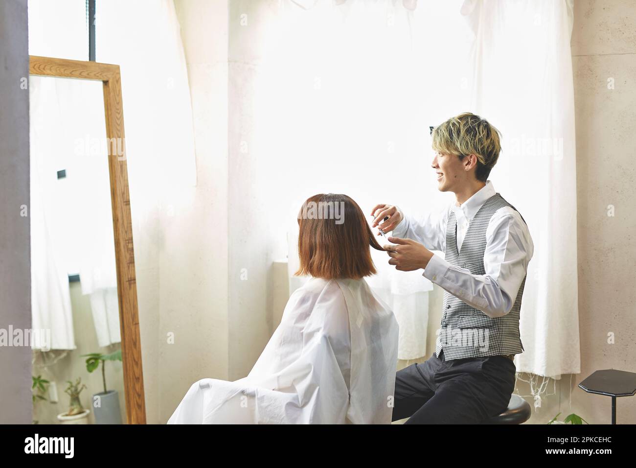 Hairdresser cutting hair while talking with client Stock Photo - Alamy