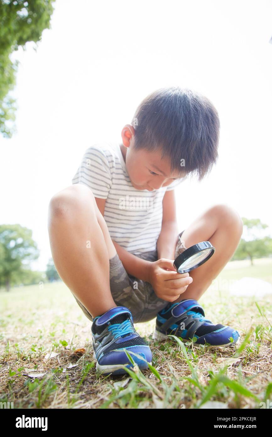 Serious looking boy watching the ground with magnifying glass Stock ...
