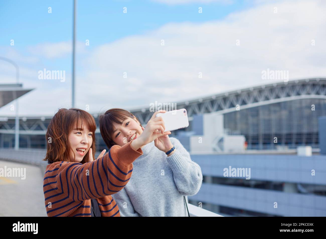 Two women taking a selfie with their smart phones at the airport Stock ...