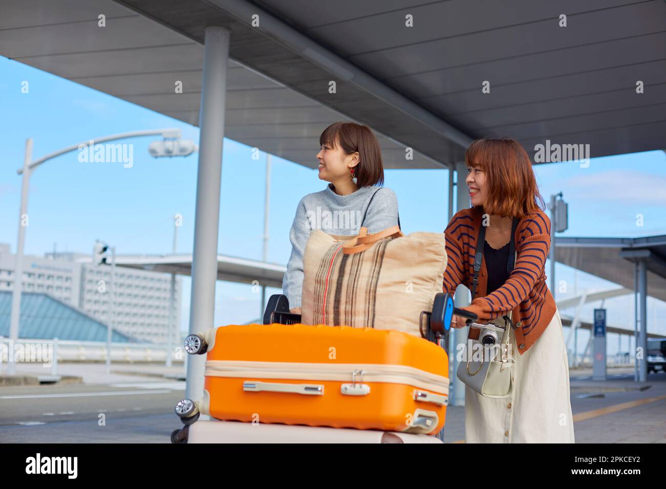 Two women walking with their suitcases on a cart Stock Photo - Alamy