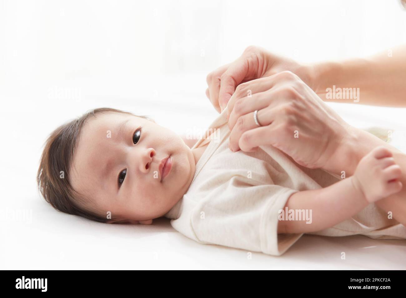 Baby being dressed by mother Stock Photo - Alamy