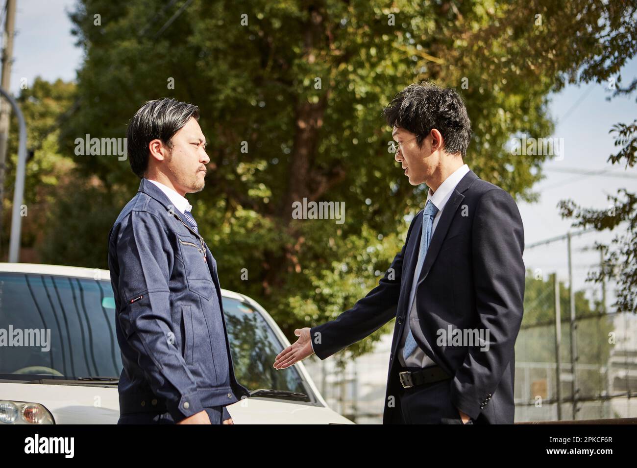 Two men with stern expressions exchanging in front of a car Stock Photo ...