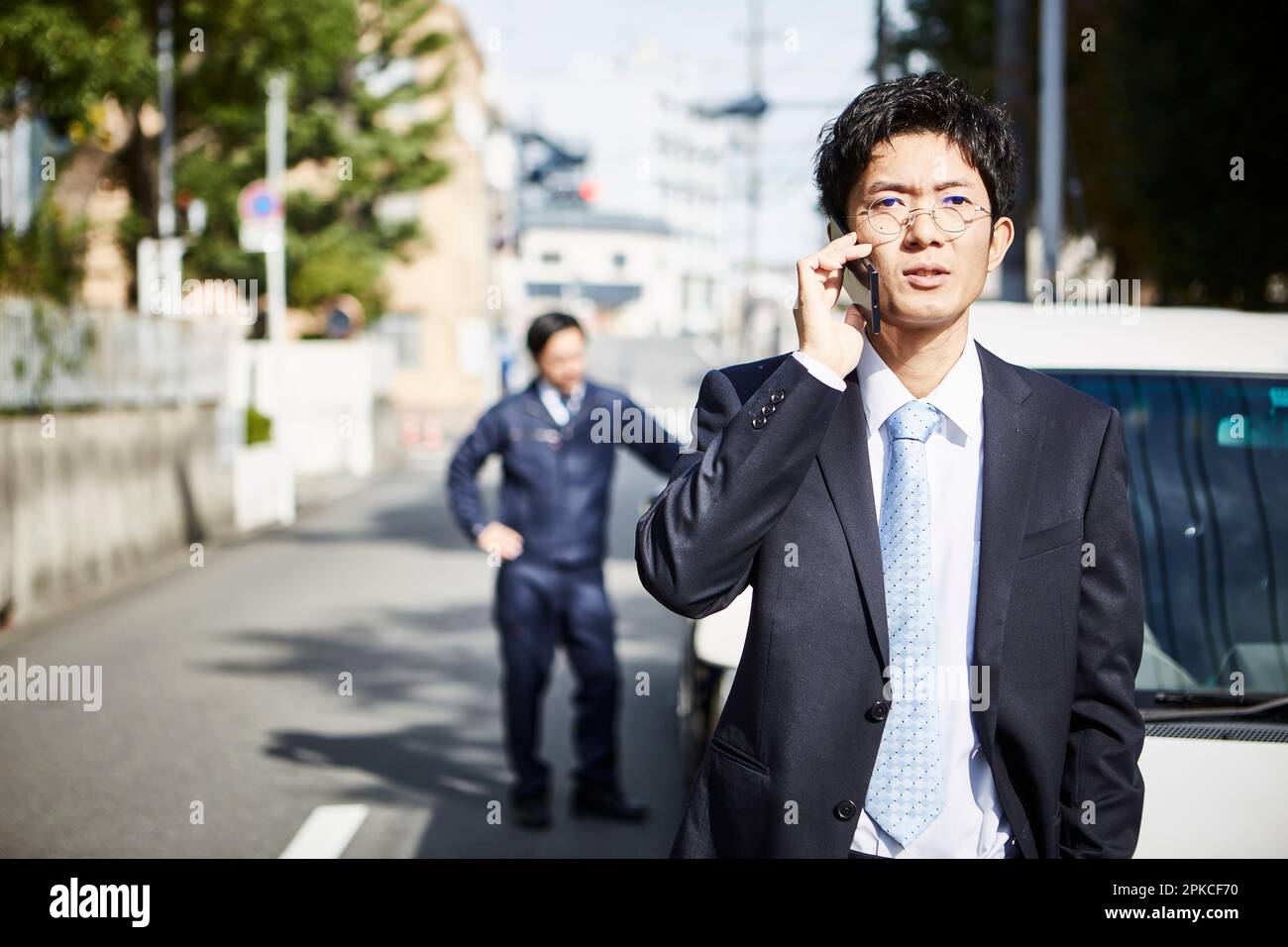 Man standing next to car and man making a phone call with a grim ...