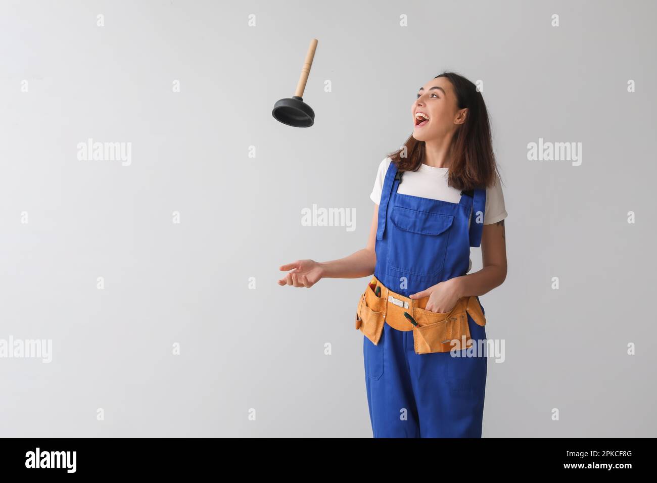 Happy female plumber and flying plunger on grey background Stock Photo ...