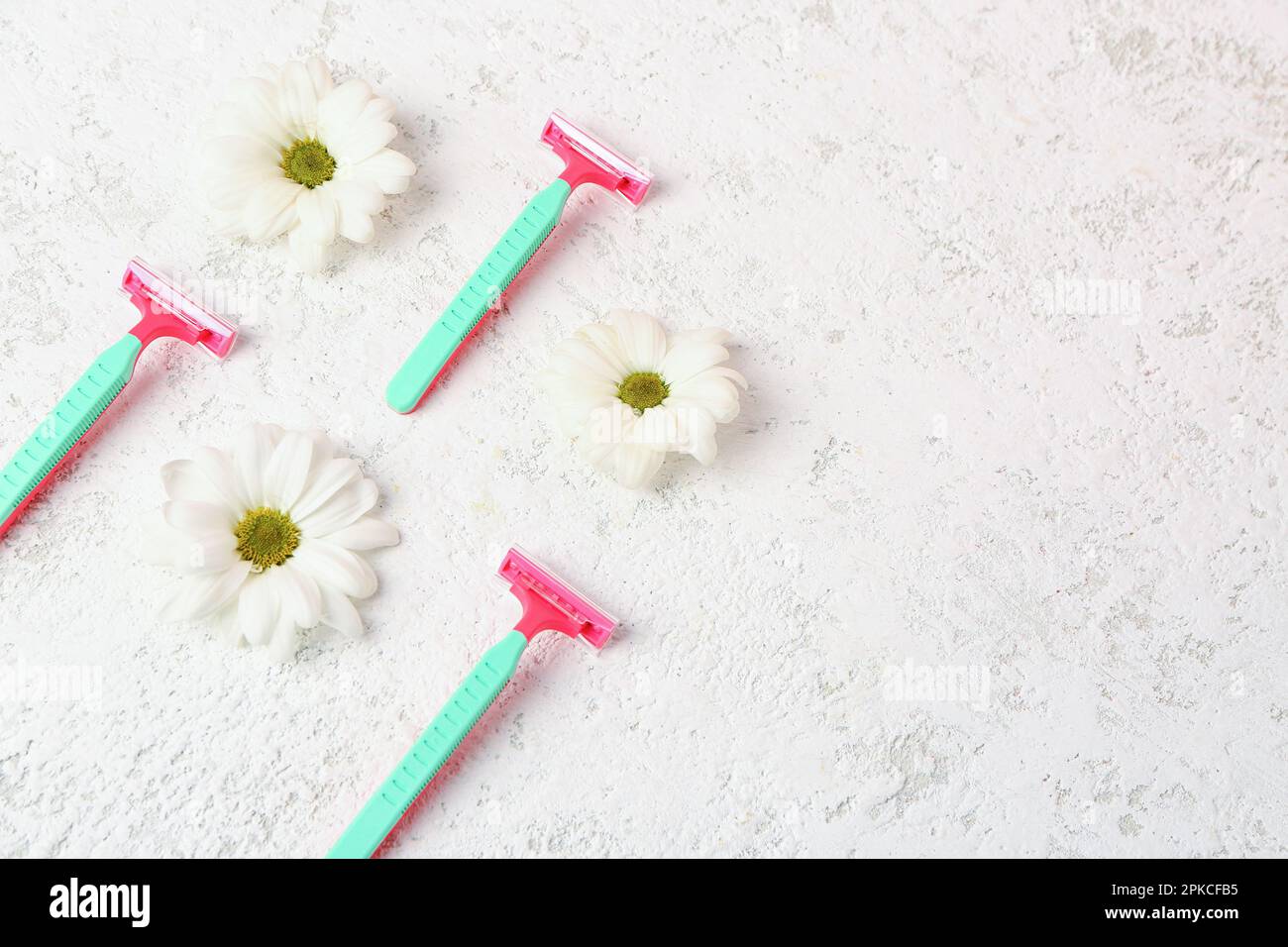 Composition with safety razors and daisy flowers on white grunge ...