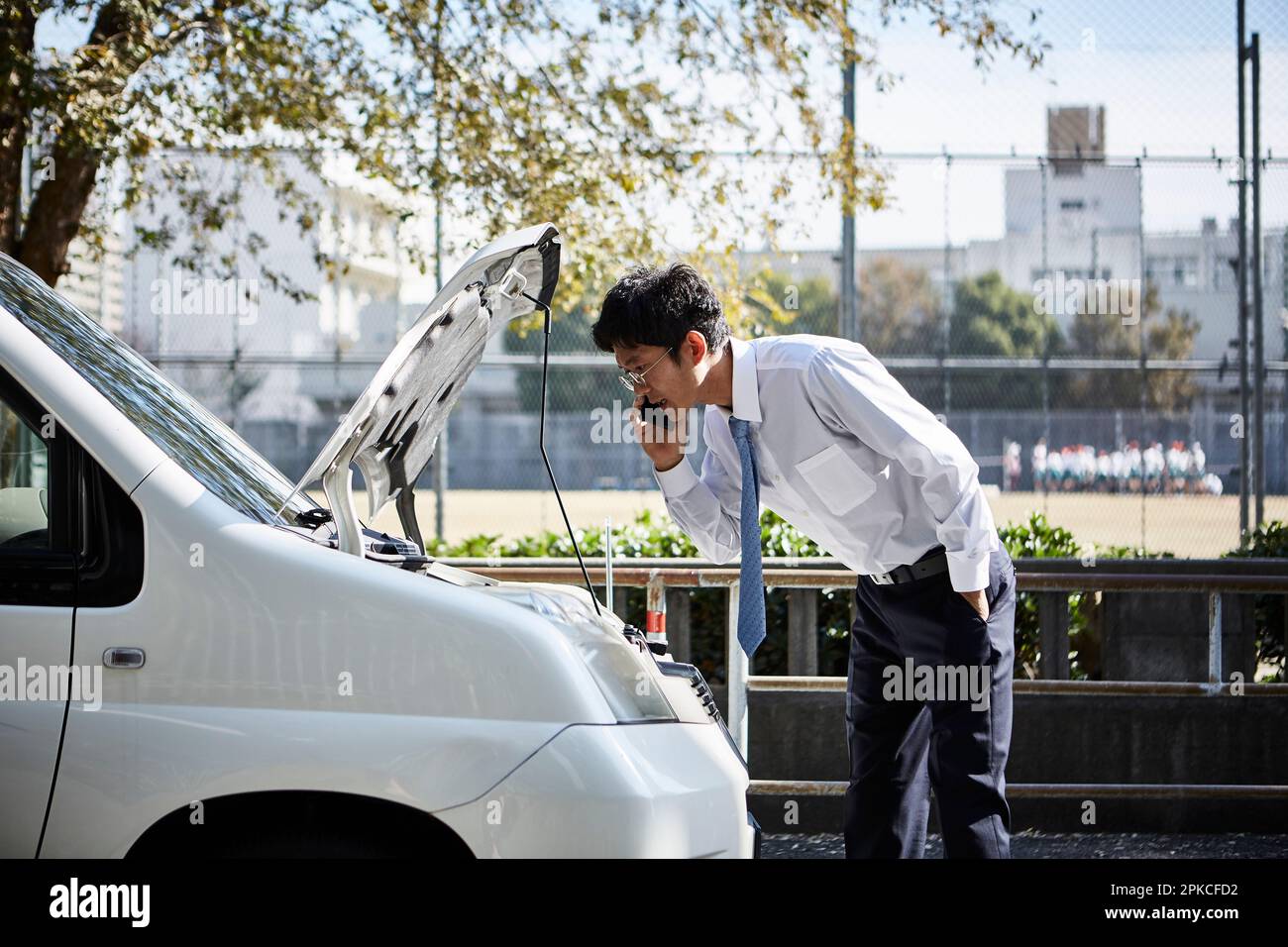 Man looking into car with open hood and making phone call Stock Photo ...