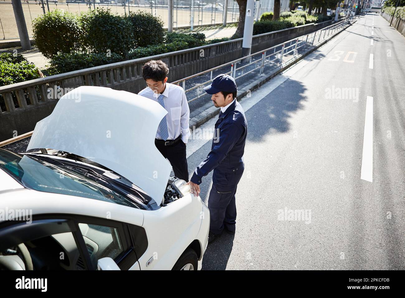 Two men talking in front of a car with an open hood Stock Photo - Alamy