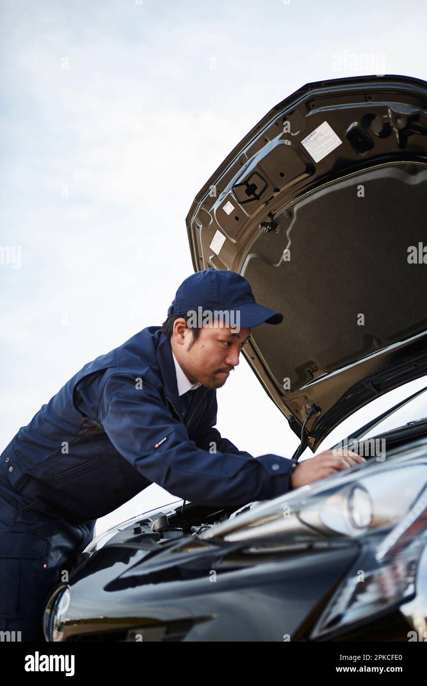Man in work clothes opening hood and peeking inside Stock Photo - Alamy