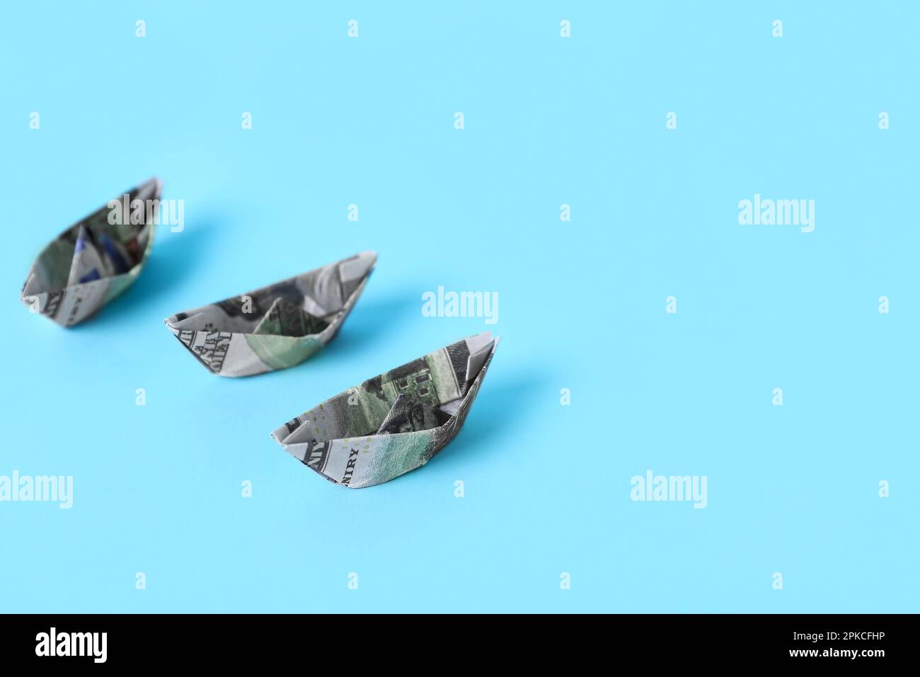 Origami boats made of dollar banknotes on blue background, closeup ...