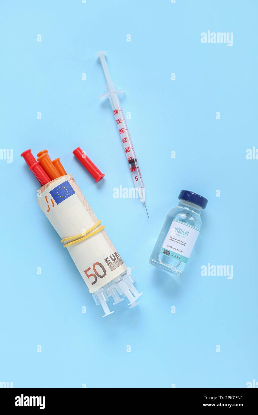 Insulin with syringes and money on blue background. Expensive medicine ...