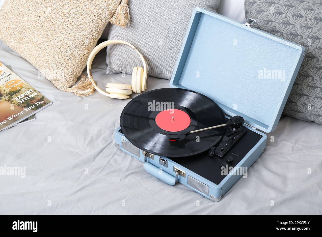Record player with vinyl disk and headphones on bed in room Stock Photo ...