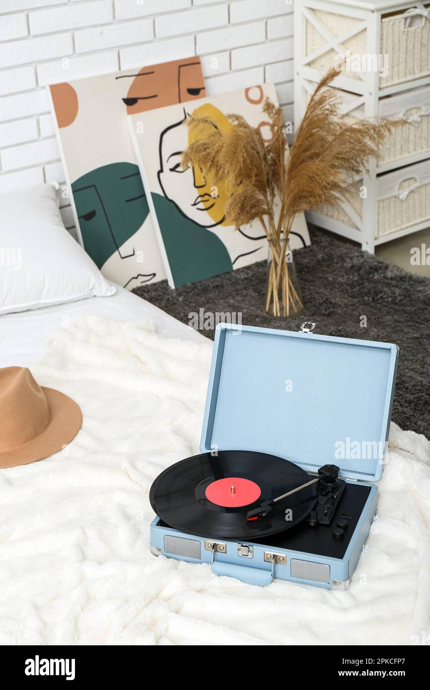 Record player with vinyl disk on bed in room Stock Photo - Alamy